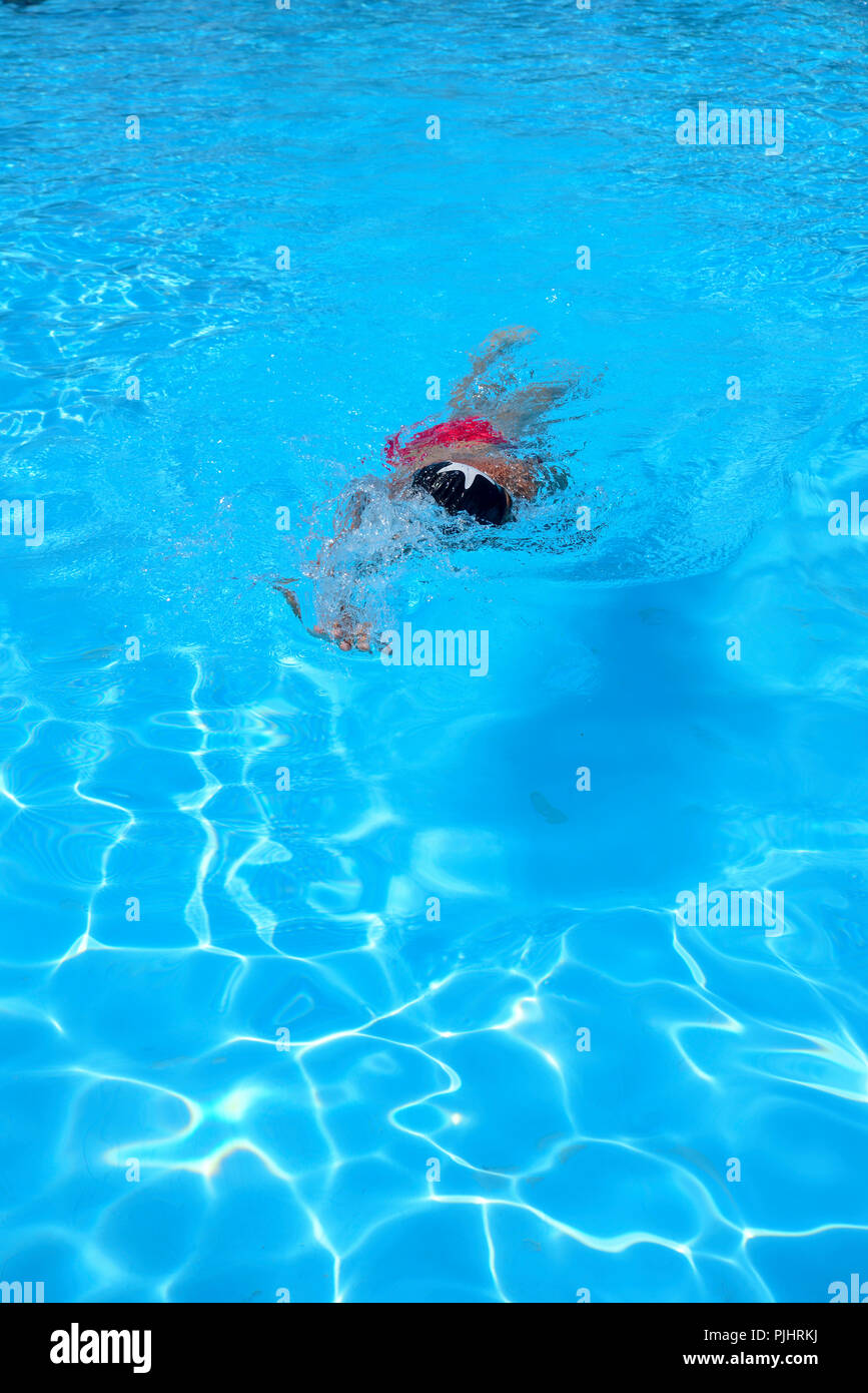 Caucasian man swims in freestyle in an outdoor pool on a sunny day. The ...