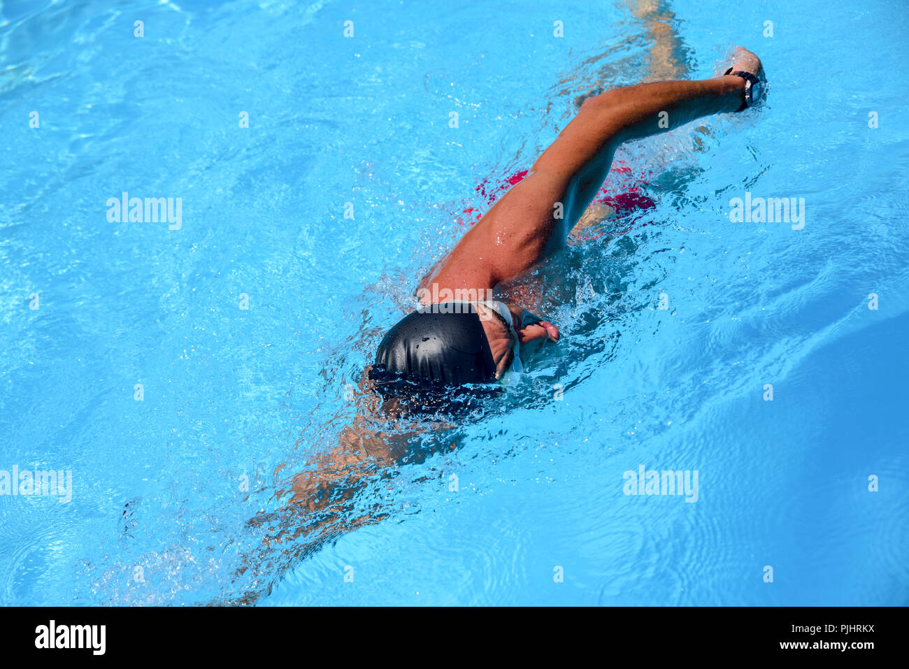 Caucasian man swims in freestyle in an outdoor pool on a sunny day. The ...