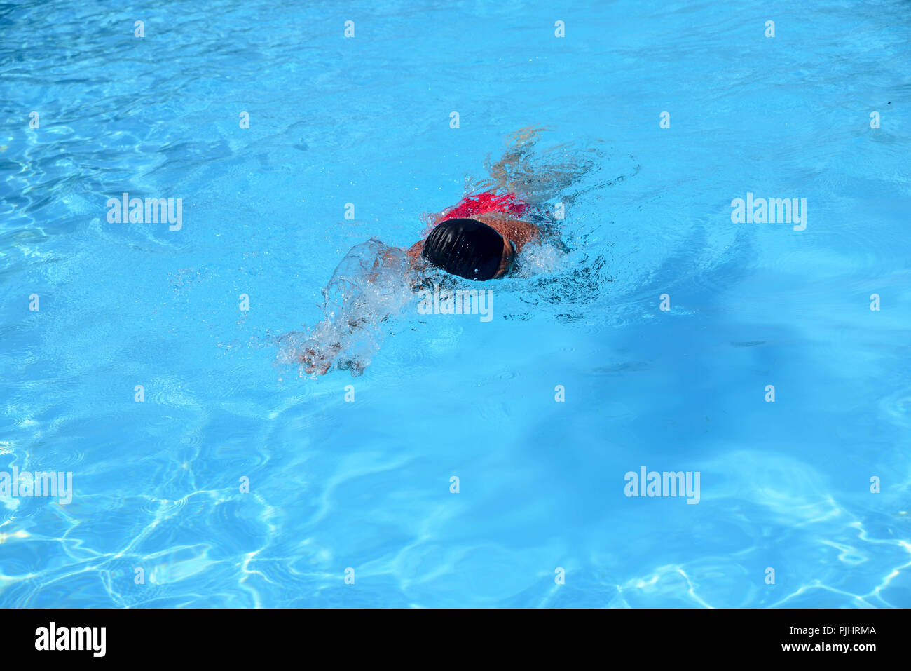 Caucasian man swims in freestyle in an outdoor pool on a sunny day. The ...