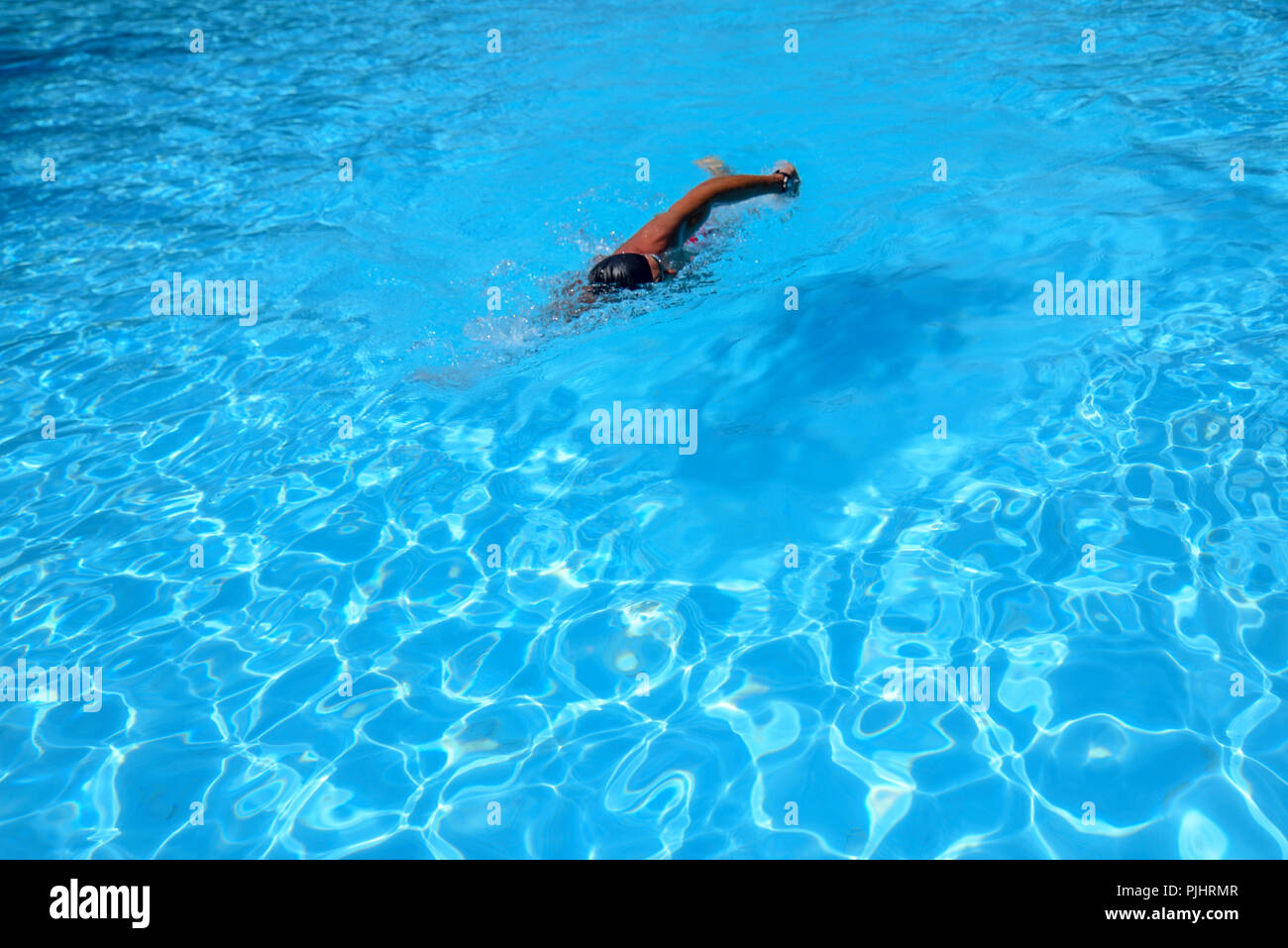 Caucasian man swims in freestyle in an outdoor pool on a sunny day. The ...
