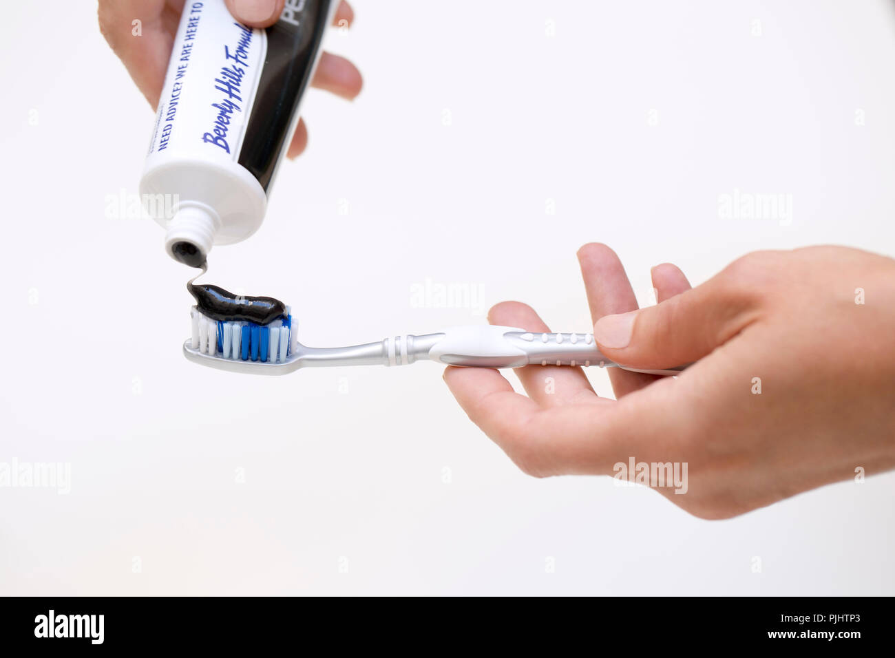 Detail hands putting toothpaste activated charcoal on a toothbrush ...