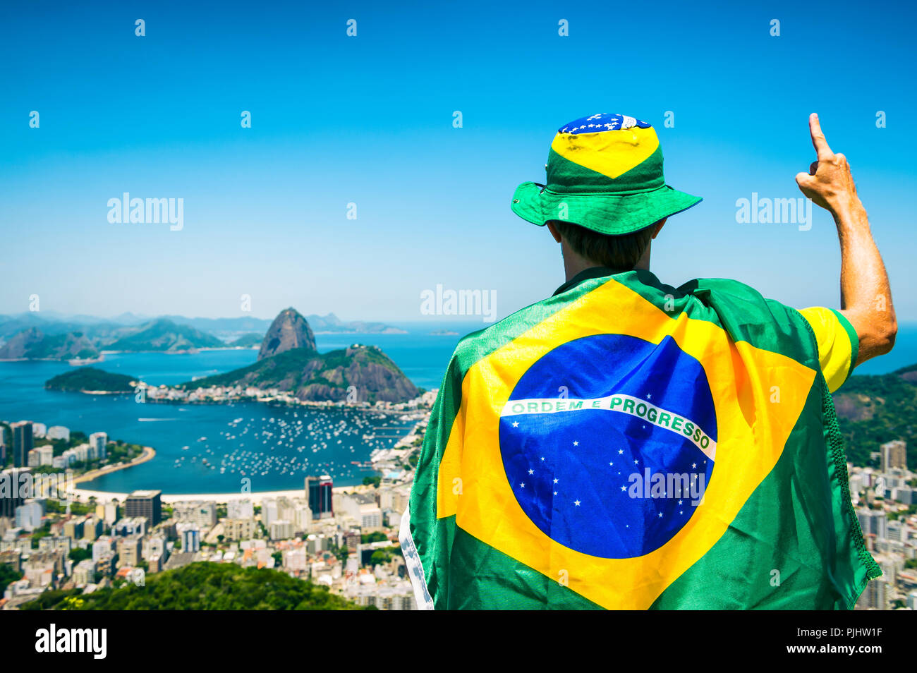 Patriotic Brazilian fan wrapped in flag holding up hand with 'number 1 ...