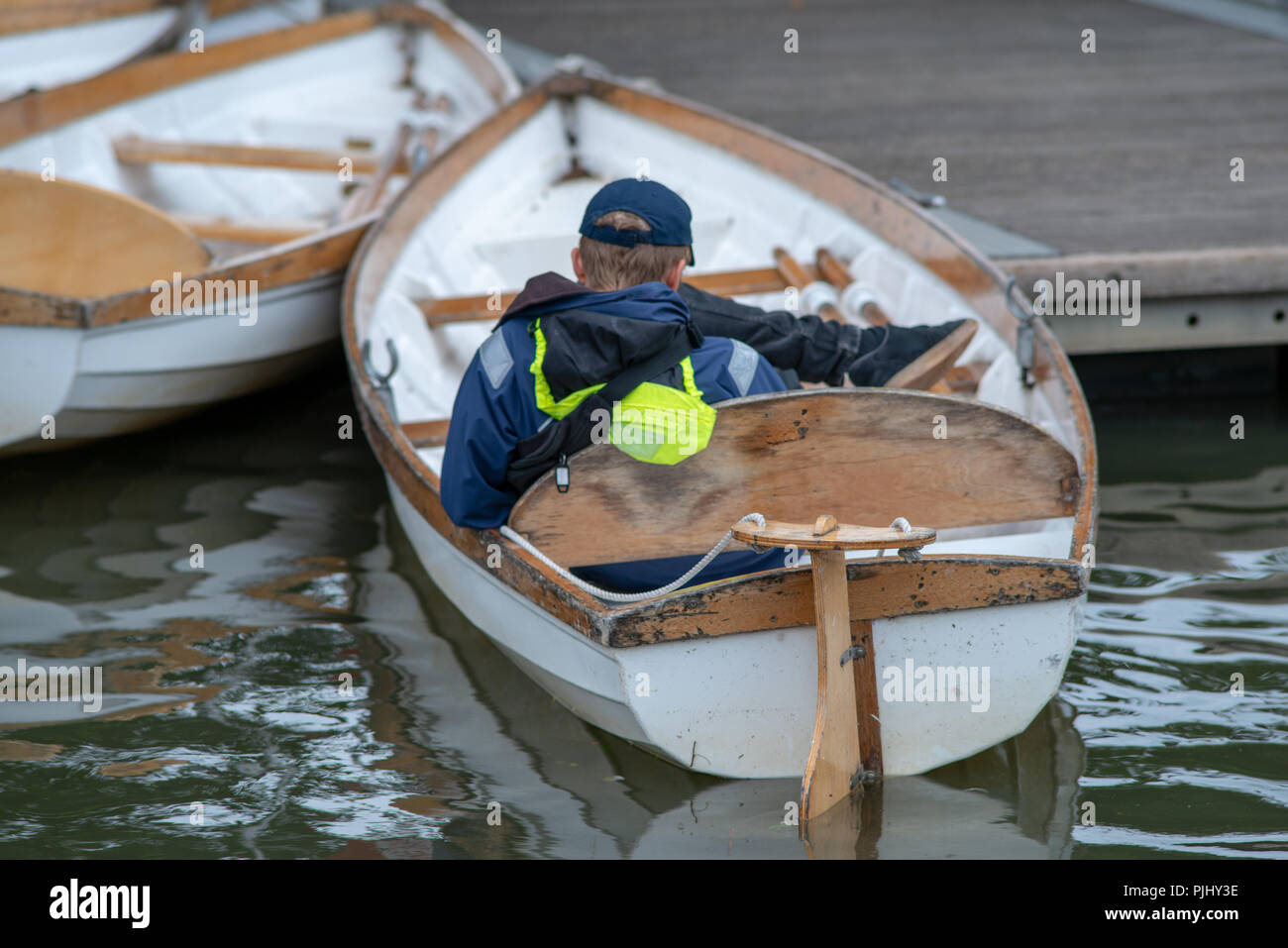 boy in blue cap and coat lazing in white rowing boat during the English ...