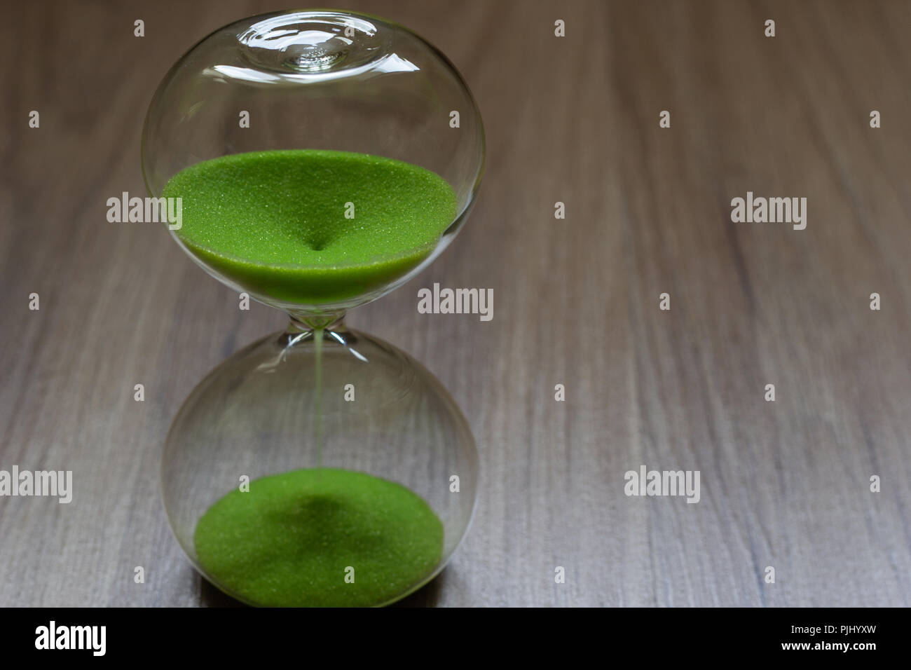 Hourglass with green sand, life time passing concept Stock Photo - Alamy