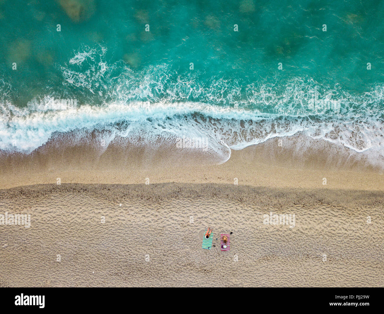 Aerial view of the amazing idyllic beach with two lonely people near ...