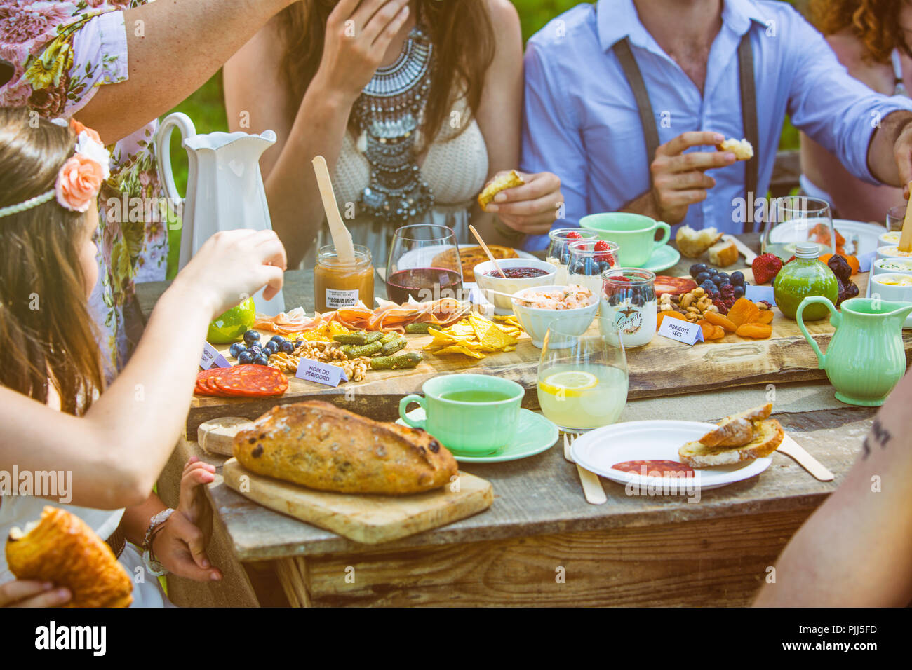 Close up of a group of young people seated at a brunch in the country ...