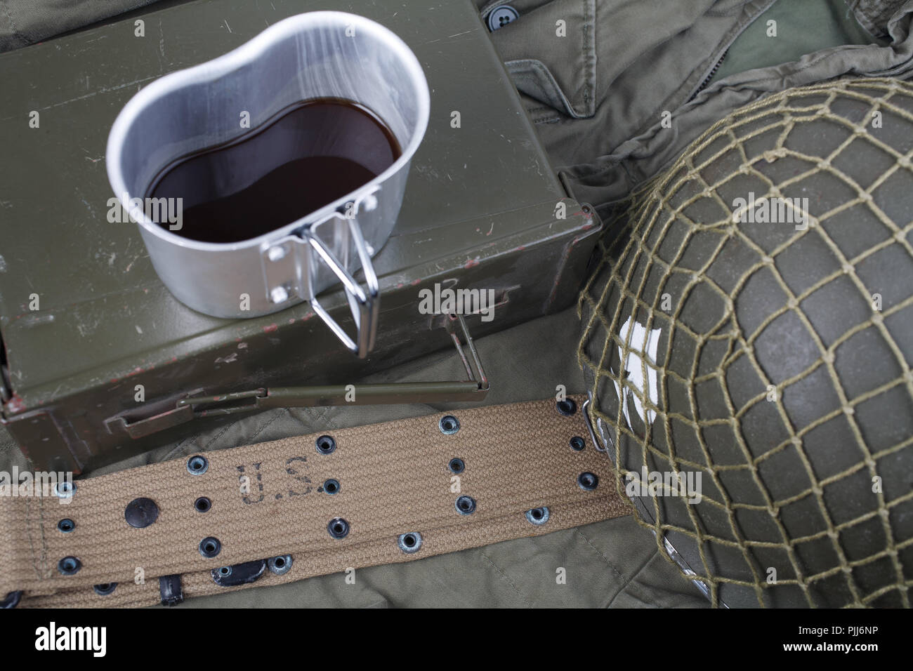 a cup of coffee with ww2 period us army military equipment on green ...