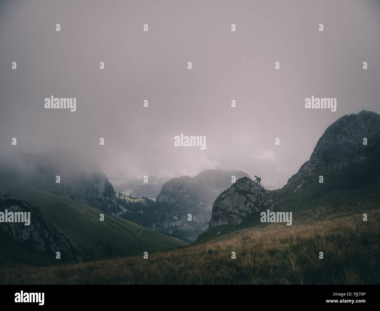 Cloudy views in the Swiss Alps with a person climbing on the ridge ...