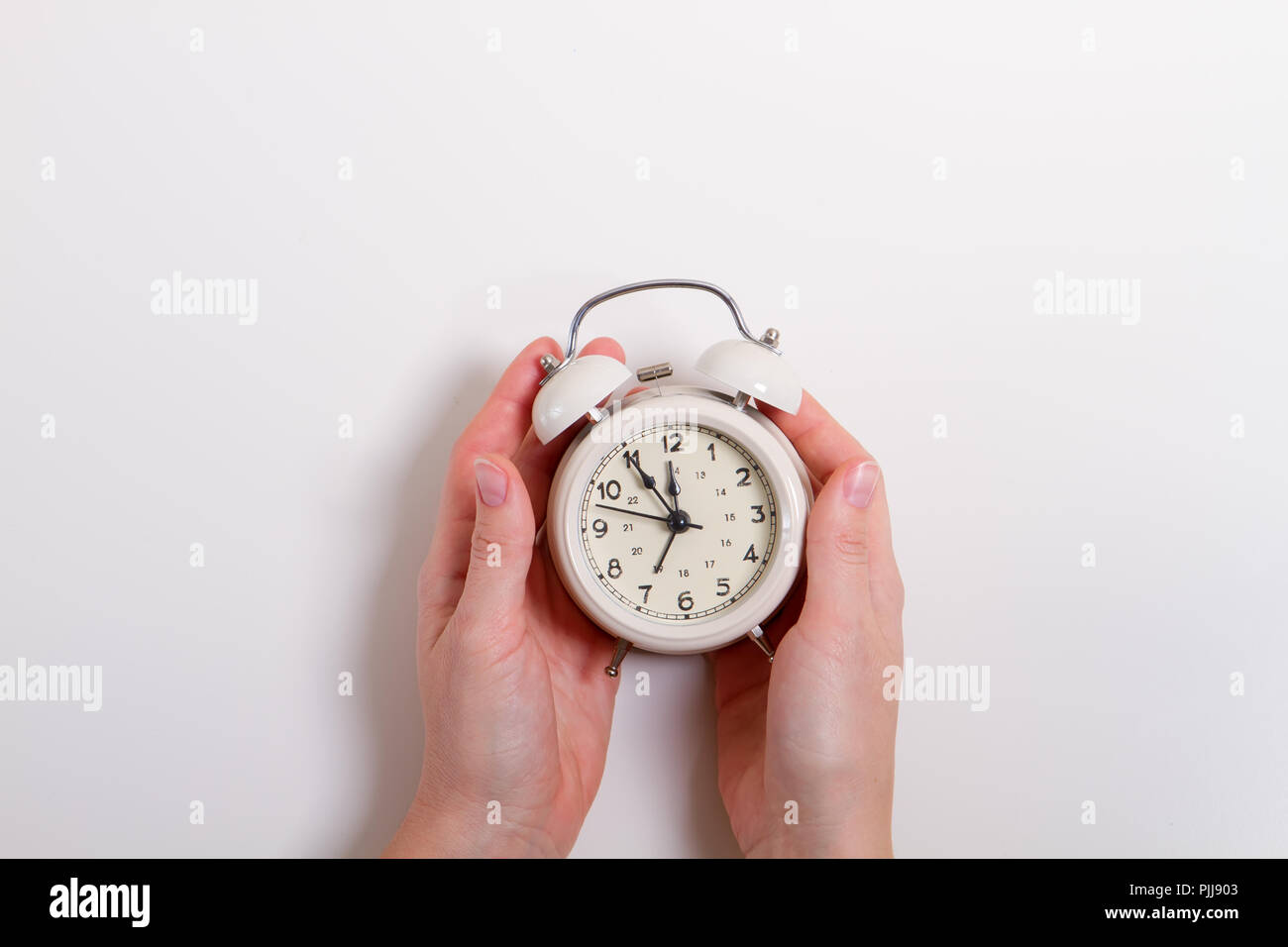 Woman's hand Holding an alarm clock Stock Photo - Alamy