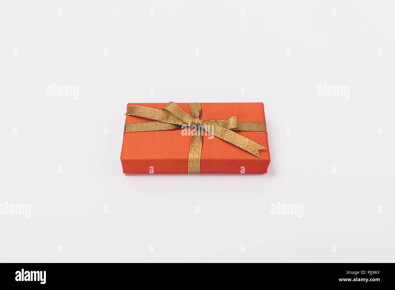 One rectangular red gift box with gold ribbon on white background ...