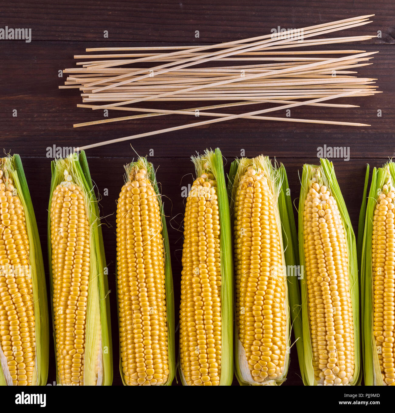 fresh ripe corn cobs on a brown wooden board, top view Stock Photo - Alamy