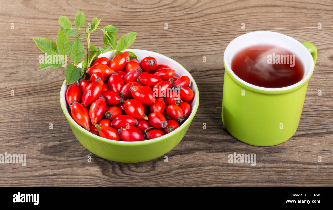 Rosehip tea. Red briar fruit pile in bowl. Wood background. Rosa canina ...