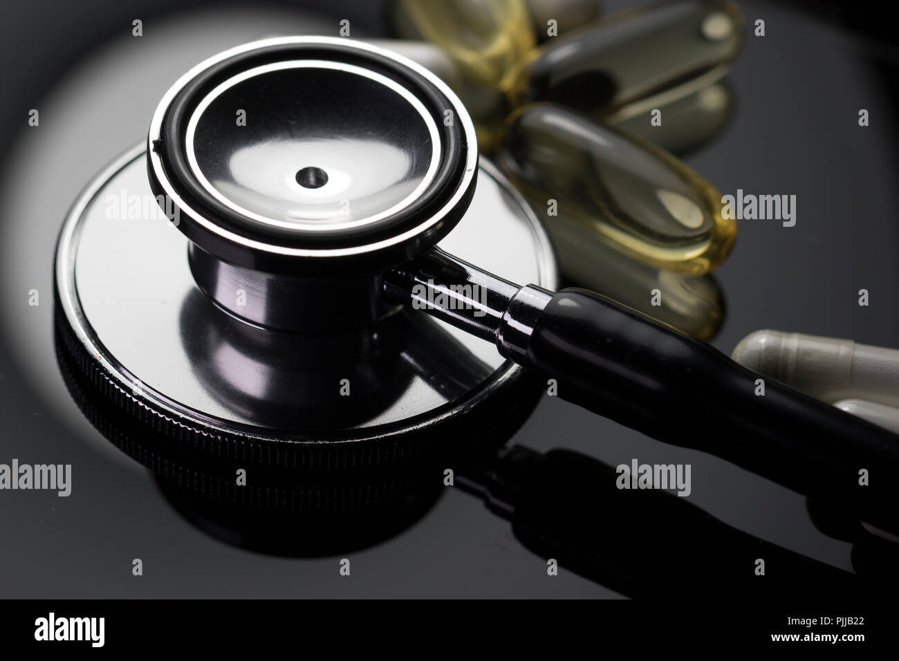 Stethoscope, vitamins and pills close up on a black table. Medical care ...