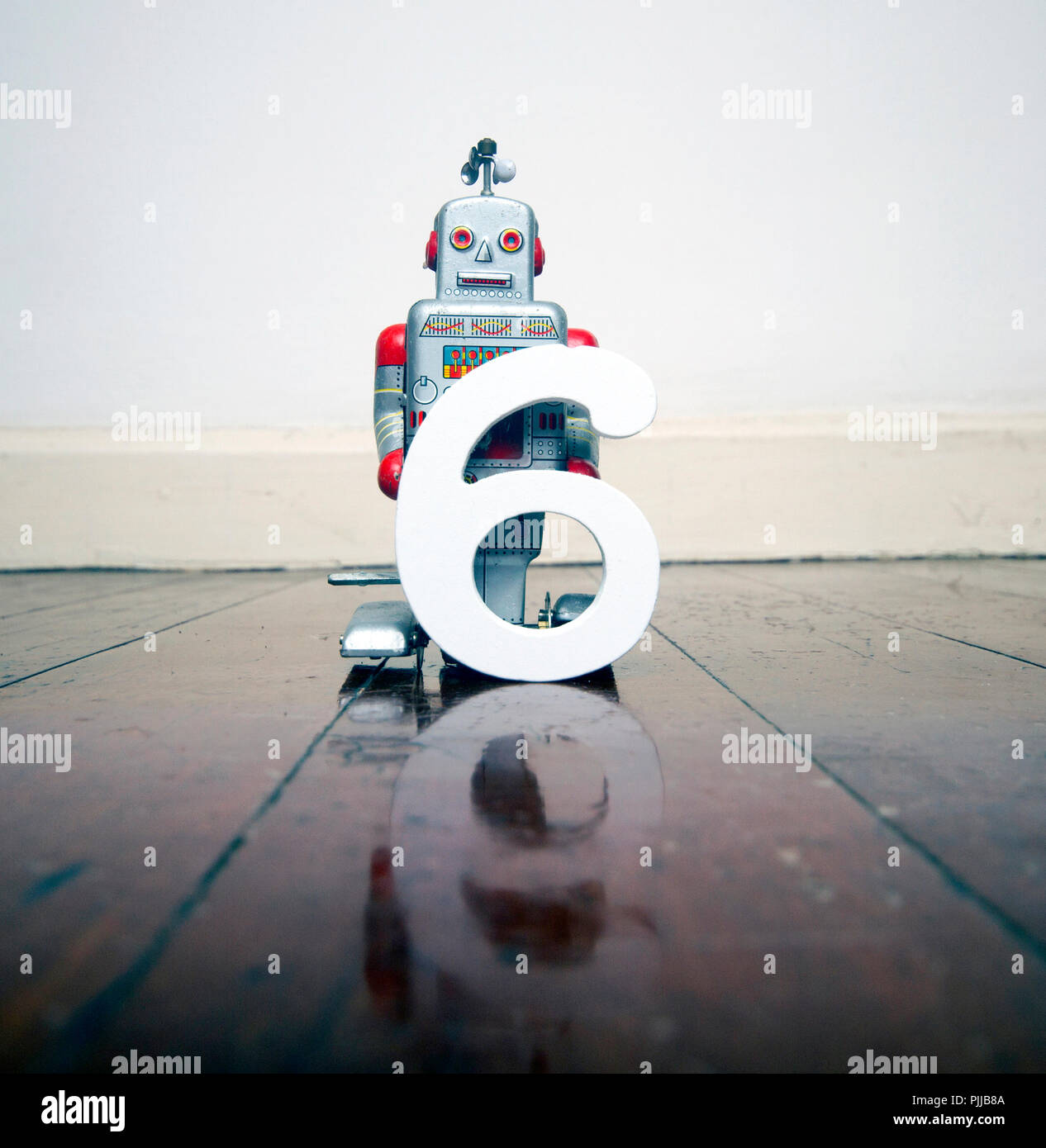 number 6 robot toy on a woden floor with reflection Stock Photo - Alamy