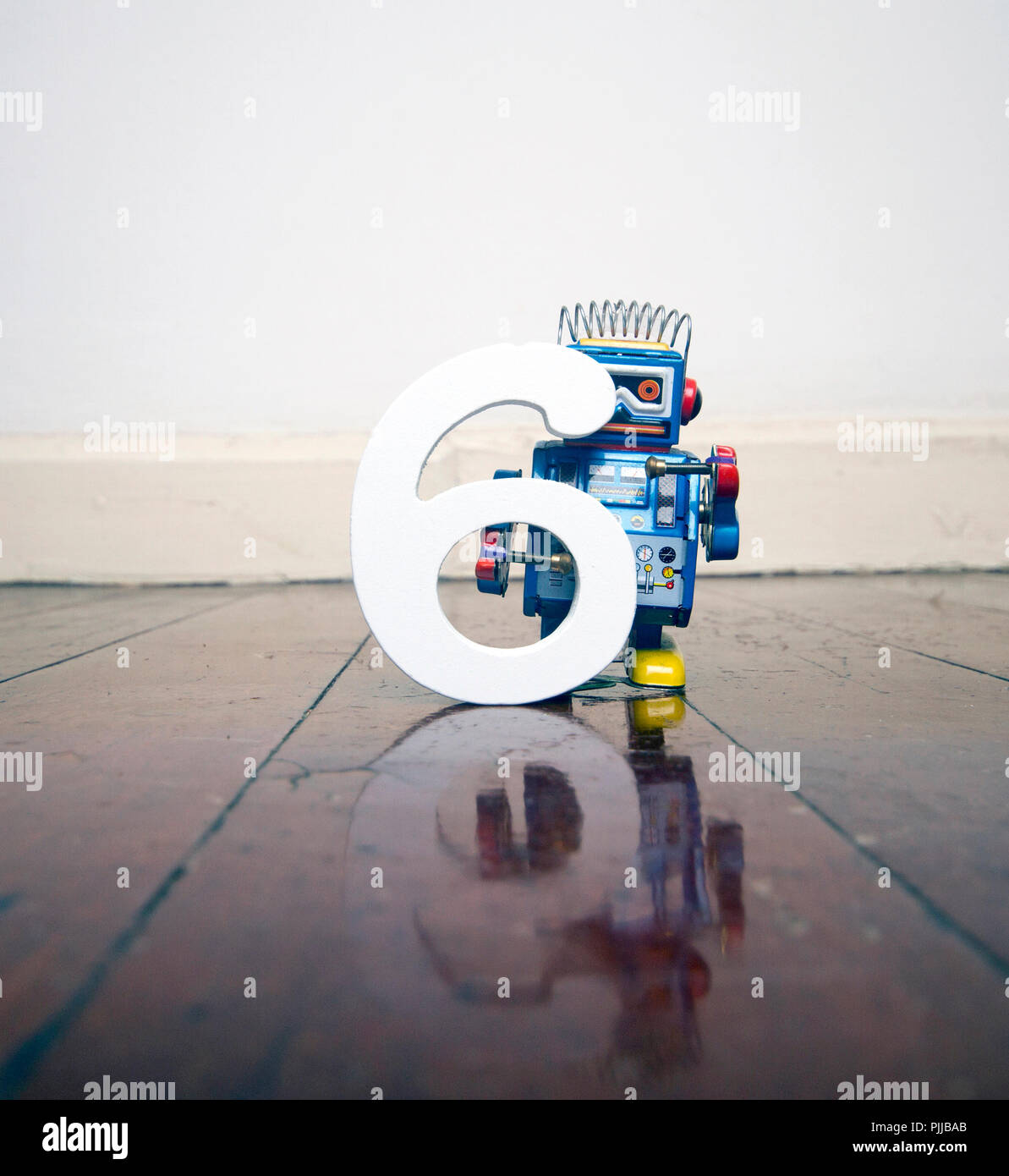 number 6 robot toy on a woden floor with reflection Stock Photo - Alamy