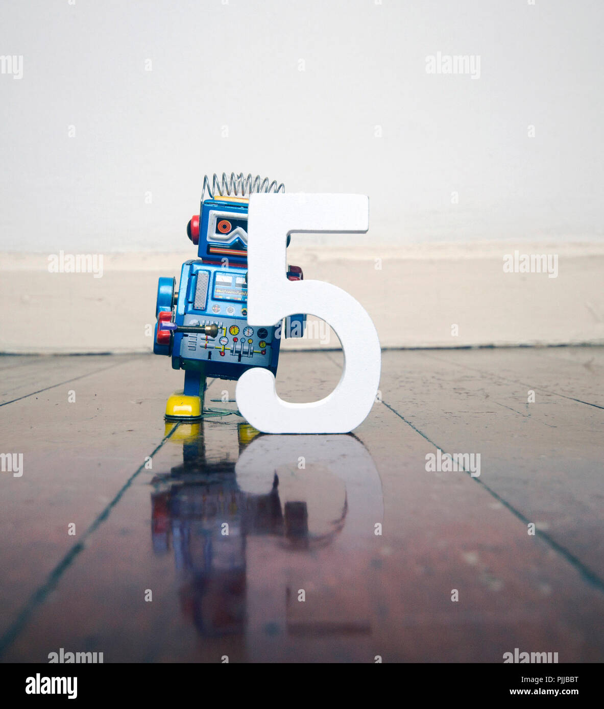 number 5 robot toy on a woden floor with reflection Stock Photo - Alamy