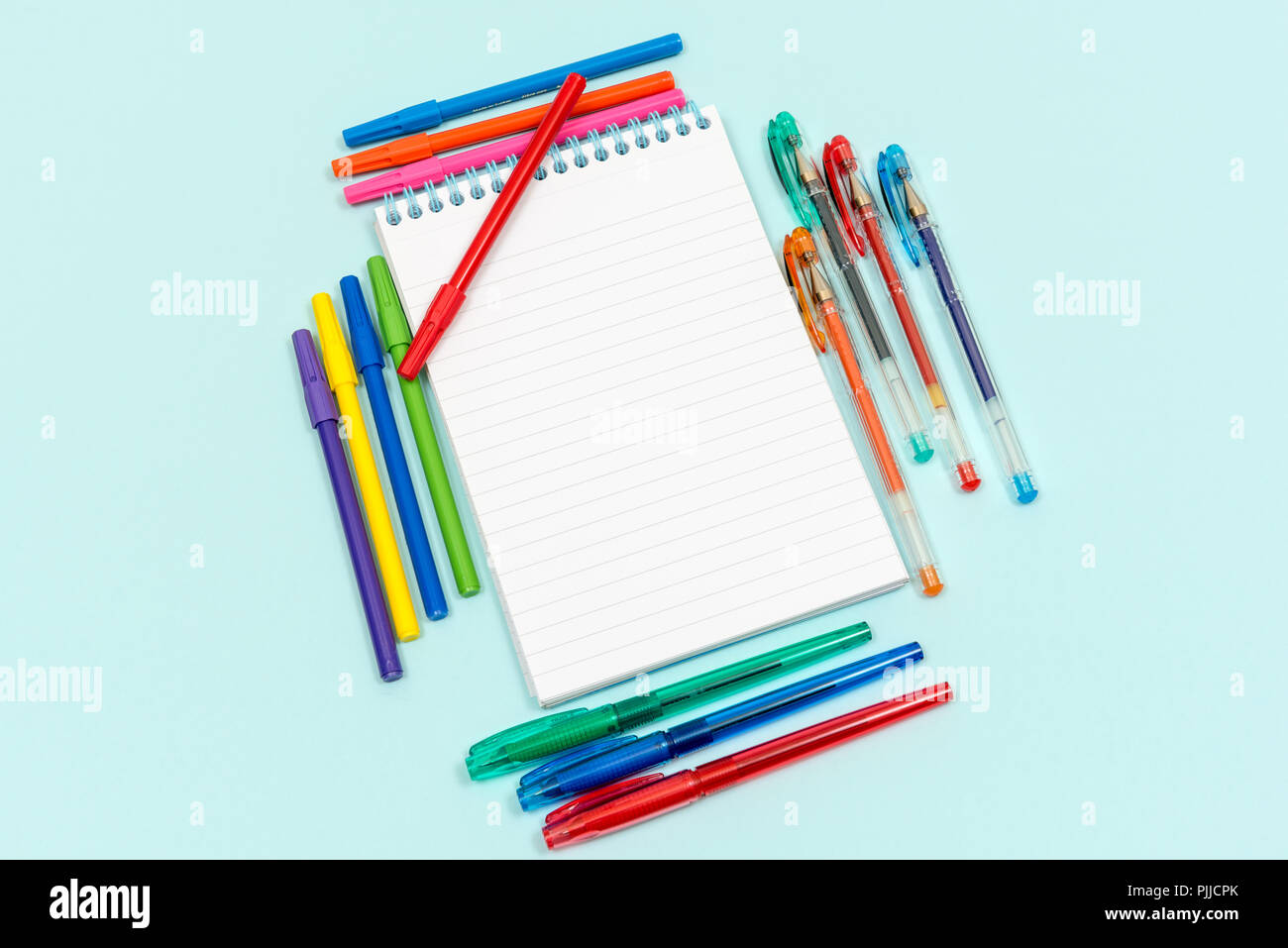 Spiral bound lined notepad surrounded by different coloured pens Stock ...