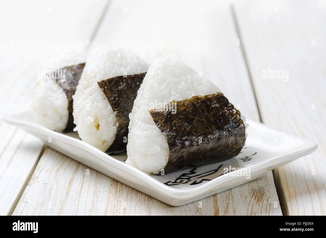 Onigiri. Rice triangle with nori seaweed on white plate Stock Photo - Alamy