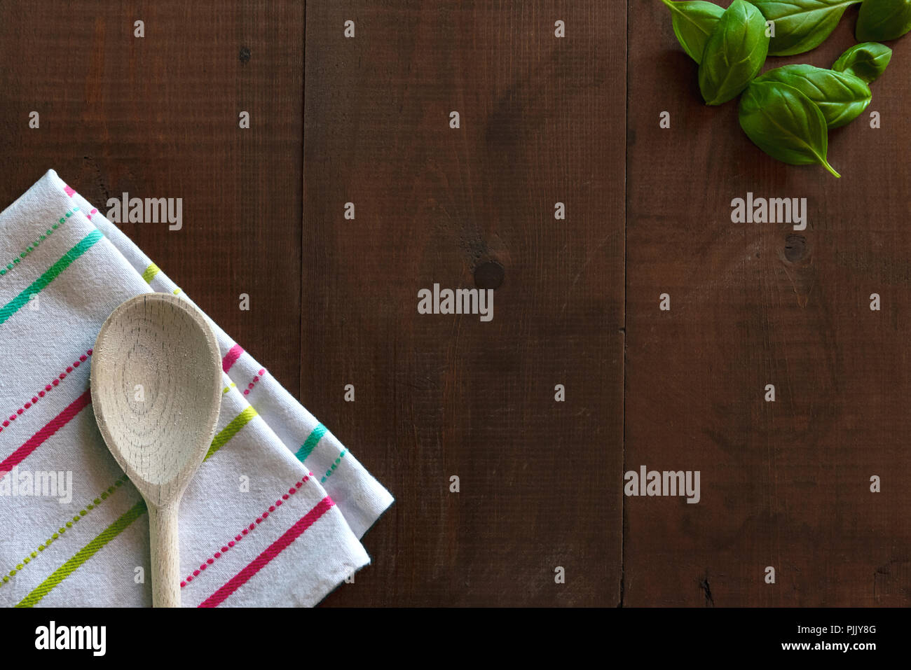 Wooden spoon lying on a cloth napkin. On a dark wood background Stock ...