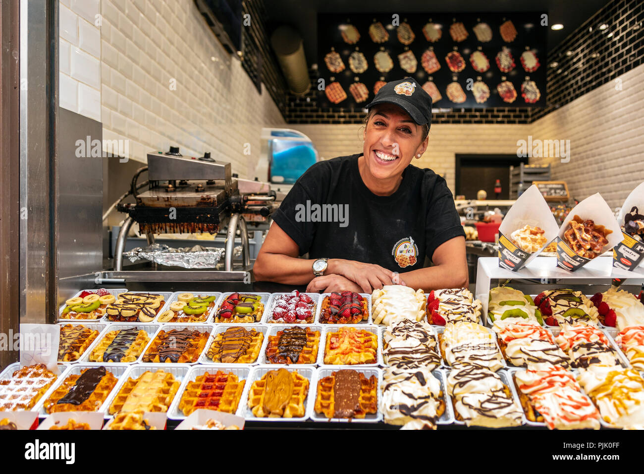 Woman working in a bakery shop selling Belgian waffles and pastries ...