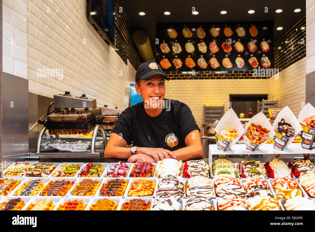 Woman working in a bakery shop selling Belgian waffles and pastries ...