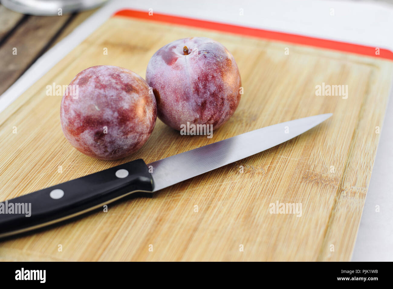 A pair of Honey Punch Pluots on a chopping board with a knife Stock ...