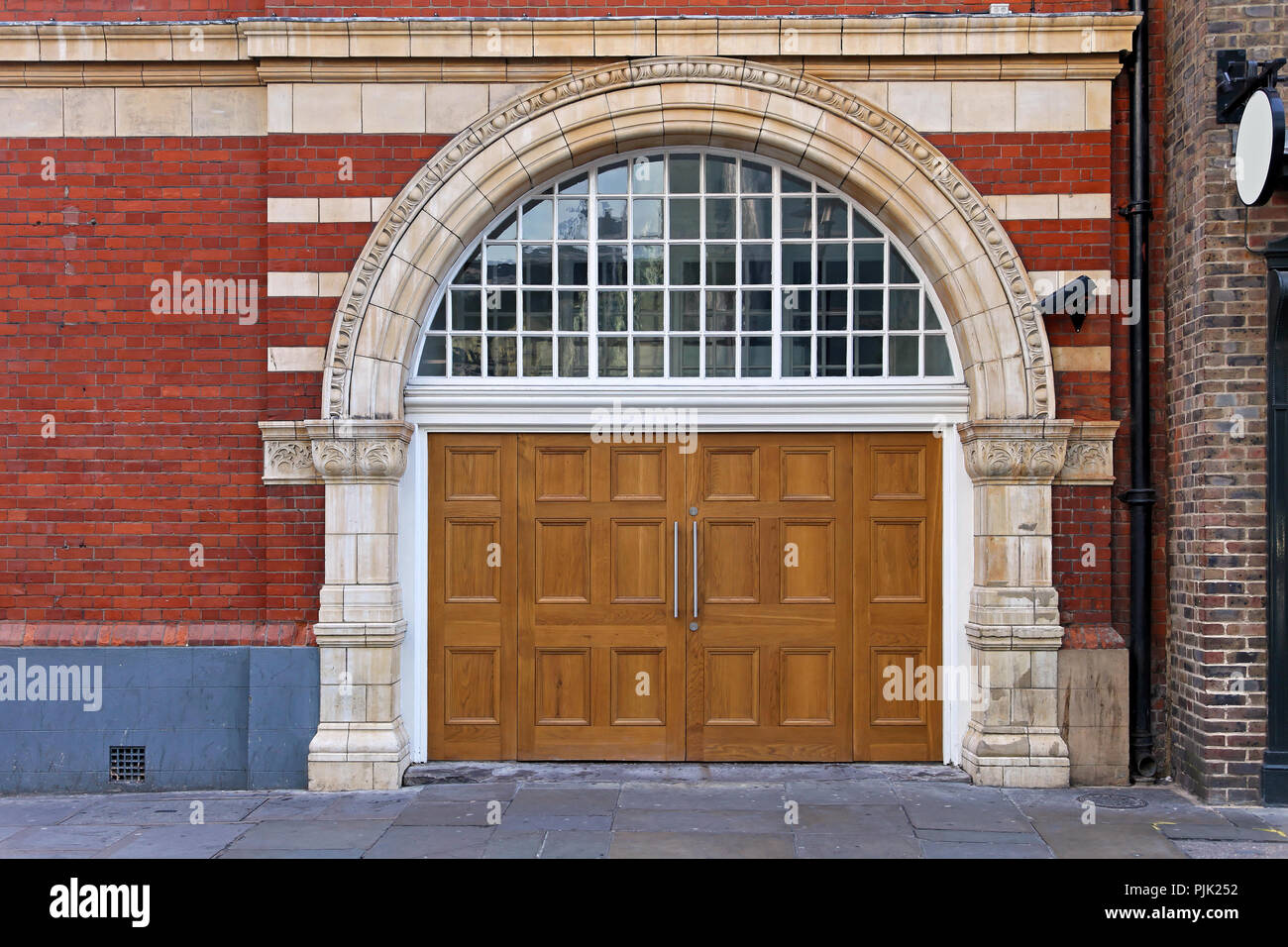 Wide wooden door and arch window at brick building Stock Photo - Alamy