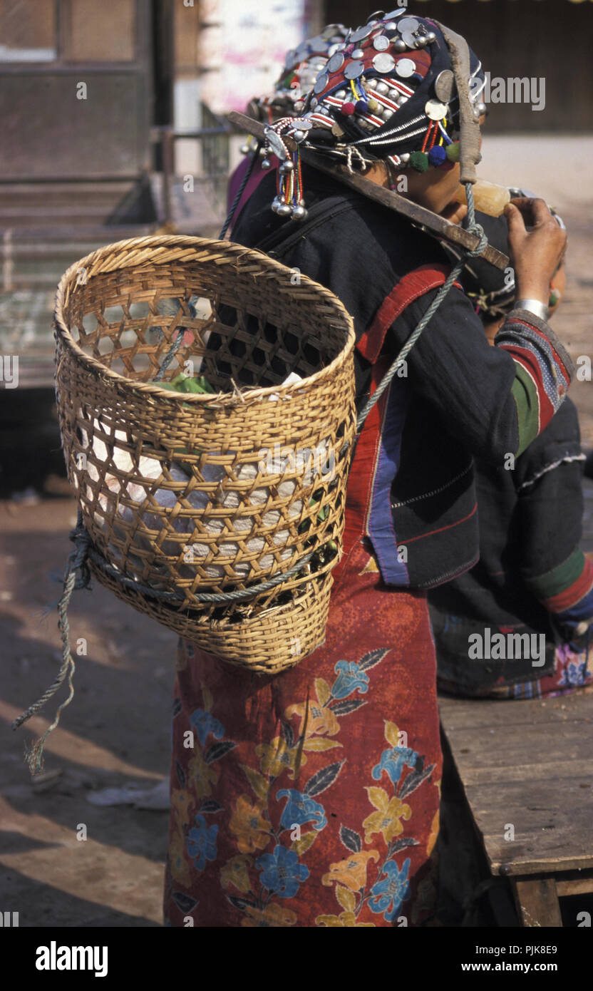 A Hmong woman wearing traditional Hmong headwear and clothing carries a ...