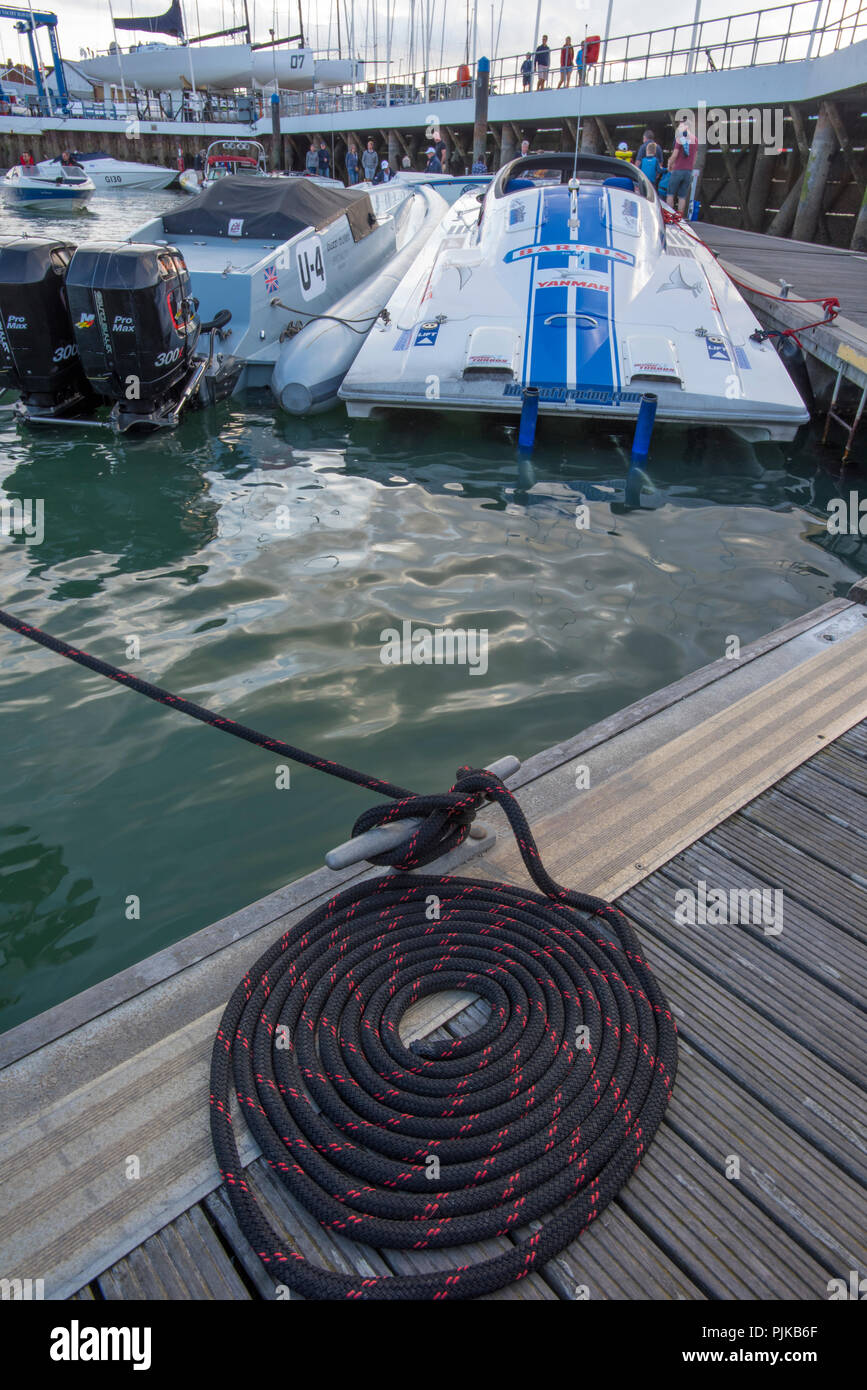 a neat coil of rope at a marina on a jetty with powerboats in the ...