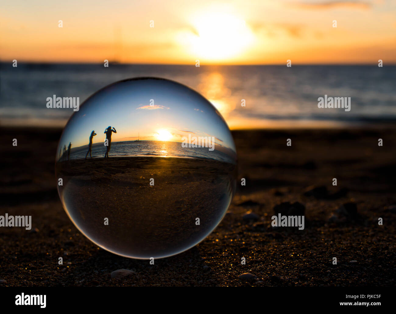 Glass Ball Captures Sunset on Beach with People in Silhouette Stock ...