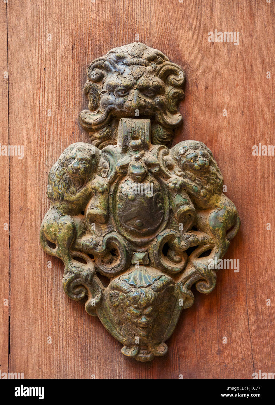 Very old door clapper with emblem between two lions, monstrous face and ...