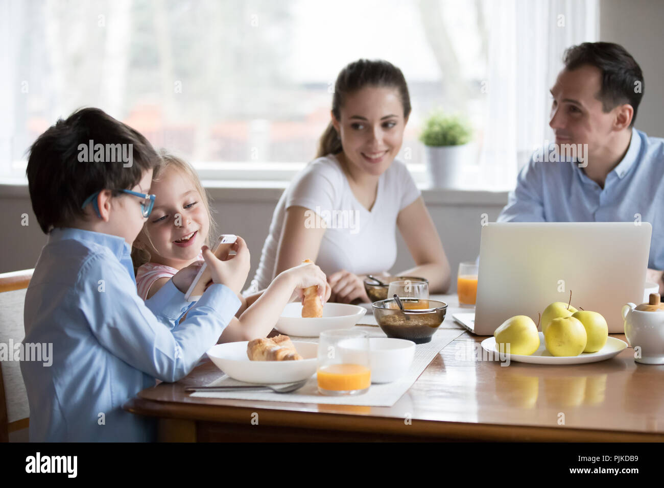 Happy parents watch excited kids playing on smartphone in kitche Stock ...