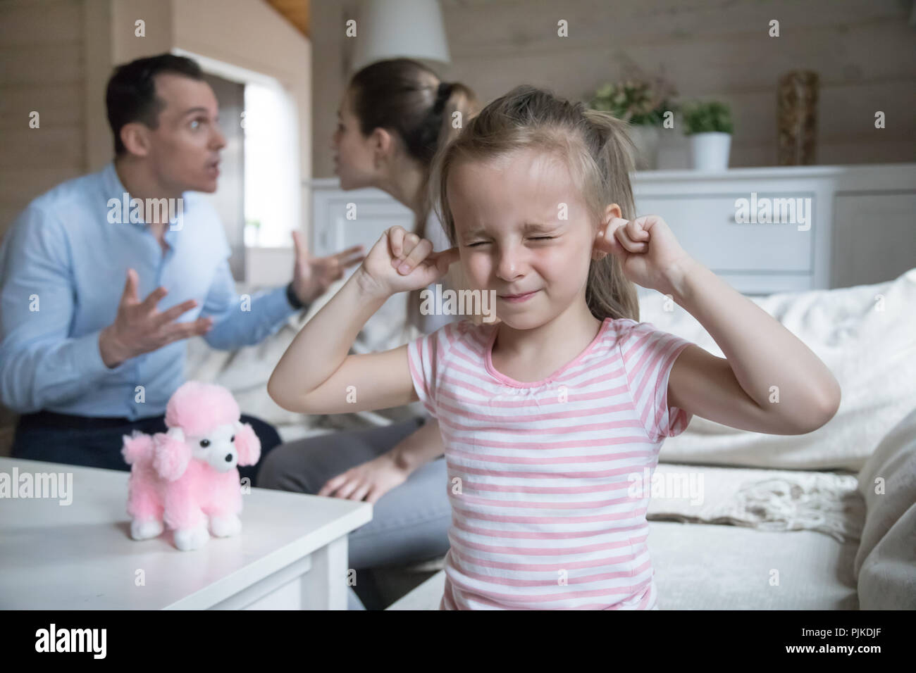 Little girl close ears refuse to hear family fight Stock Photo - Alamy