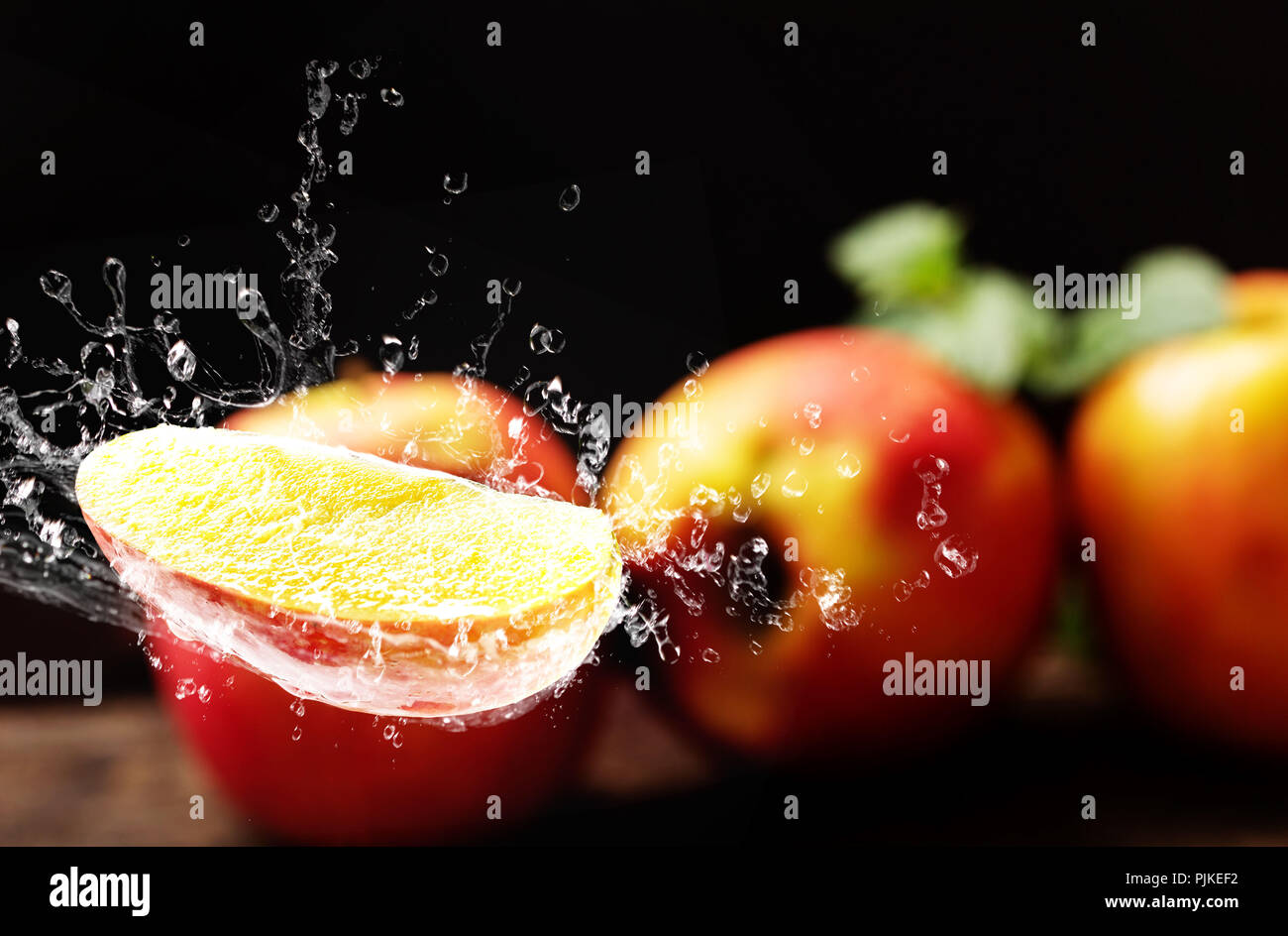 Apple with water splash in front of black background Stock Photo - Alamy