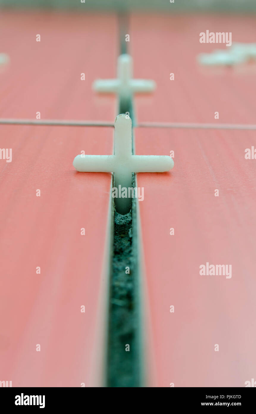Closeup of tile spacer between red ceramic tiles Stock Photo - Alamy