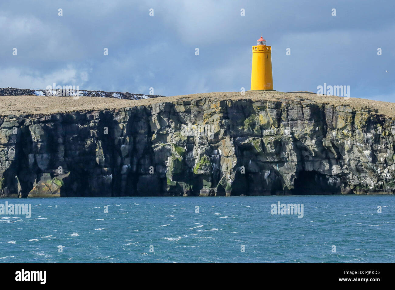 Iceland, yellow lighthouse at Reykjavik on high cliff, seen from the ...