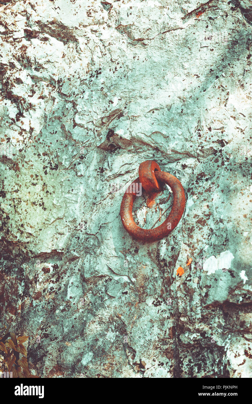 A rusty ring on a rock, antique tool for transporting goods on steep ...