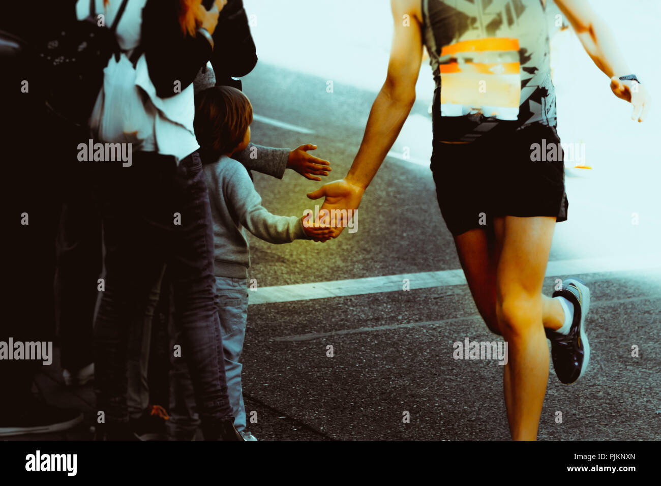 Long distance in the big city, marathon runner high fiving a little boy ...