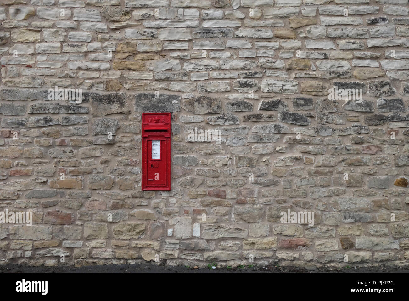 distance view of small English village post box built into large stone ...