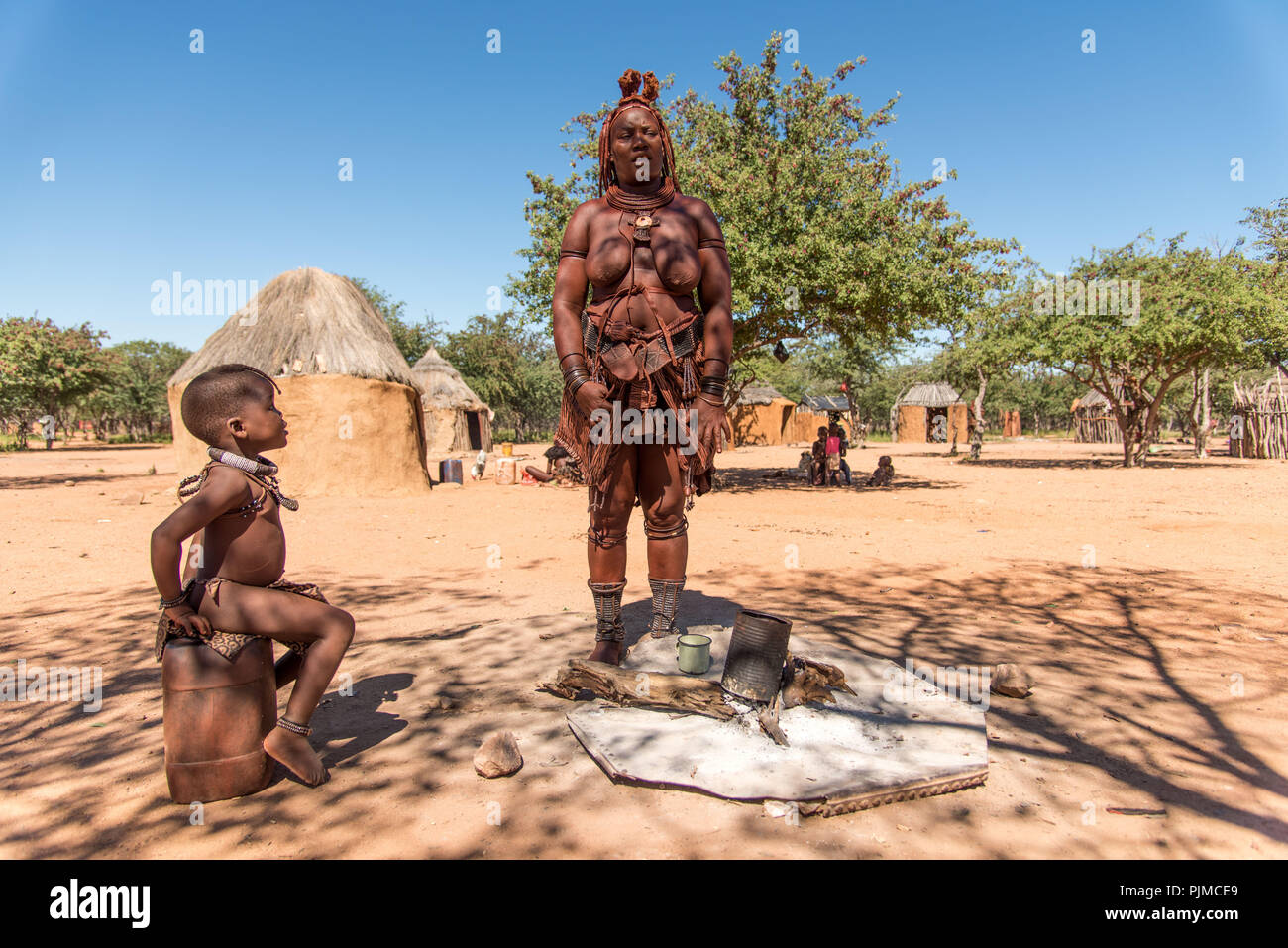 Himba girl and Himba woman at a fire pit in a Himba village in Namibia ...