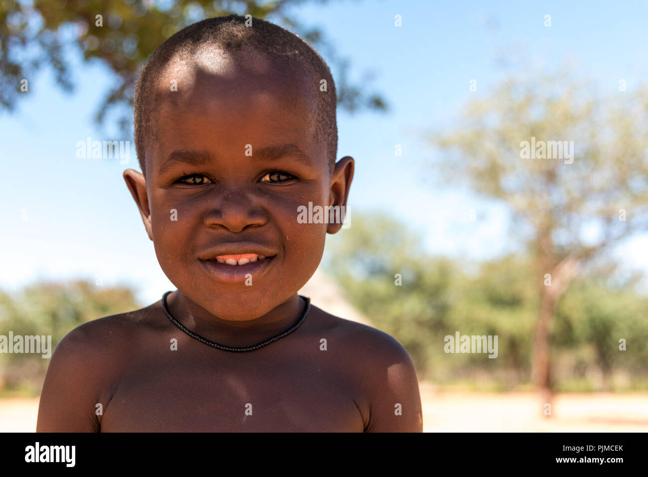 Close-up of a laughing Himba boy in a Himba village, looking into the ...
