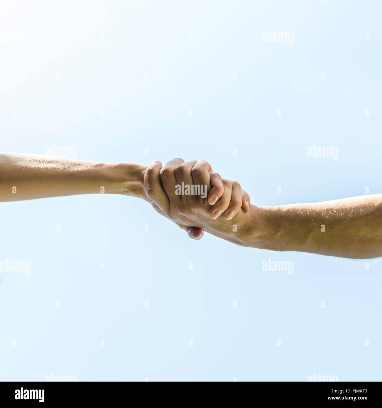 Bottom view of handshake over clear blue sky Stock Photo - Alamy