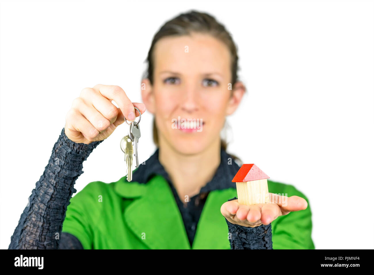 Female real estate agent holding house keys in one and wooden toy house ...