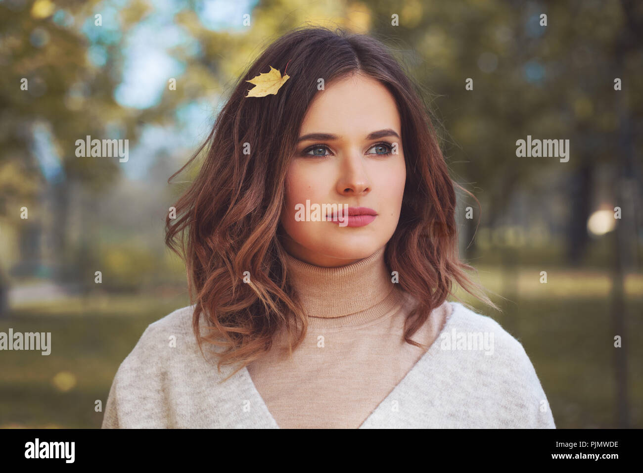 Autumn concept. Young brunette woman with fall leaf outdoor portrait ...