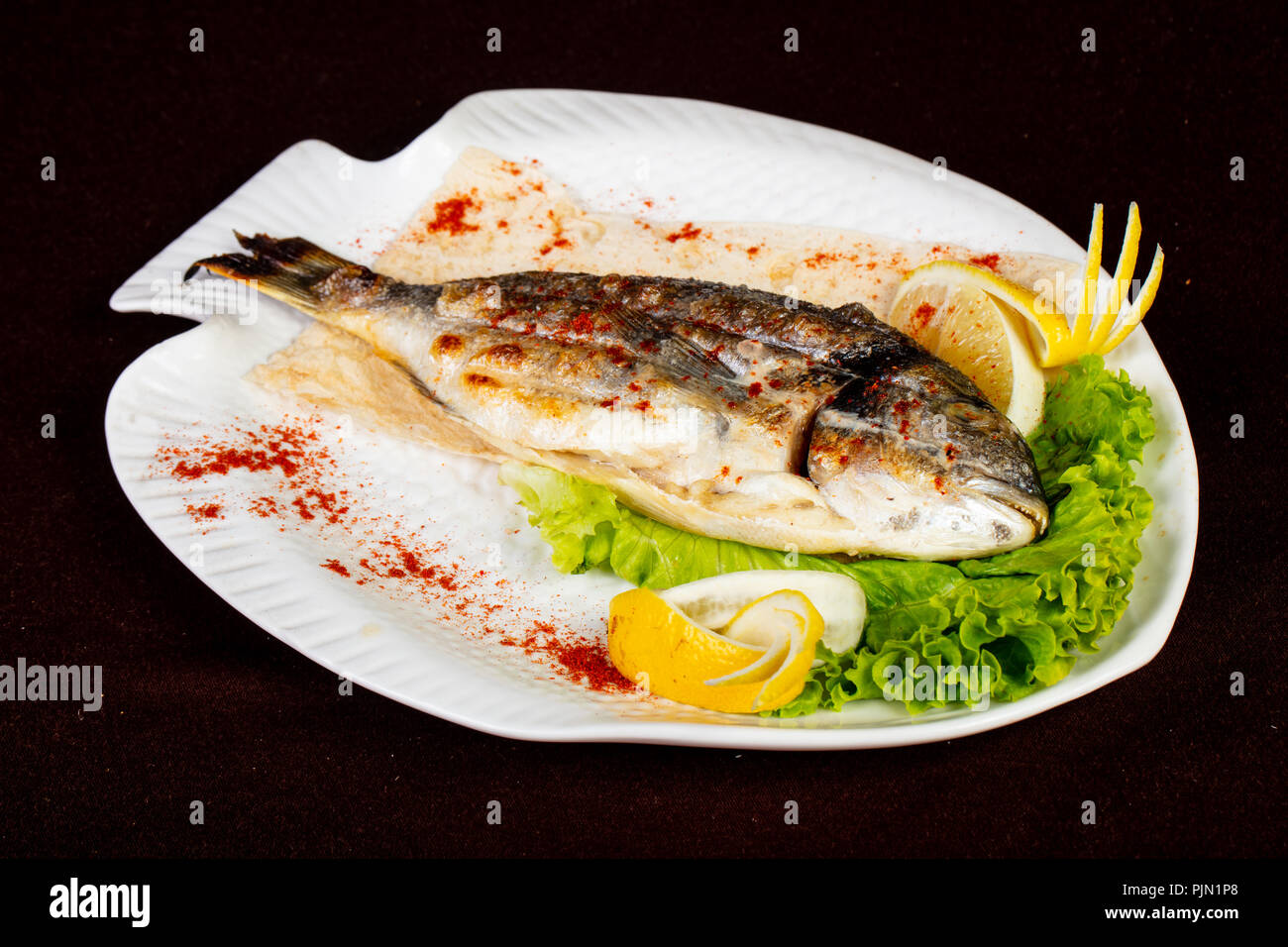 Grilled dorada fish served lemon and salad Stock Photo - Alamy