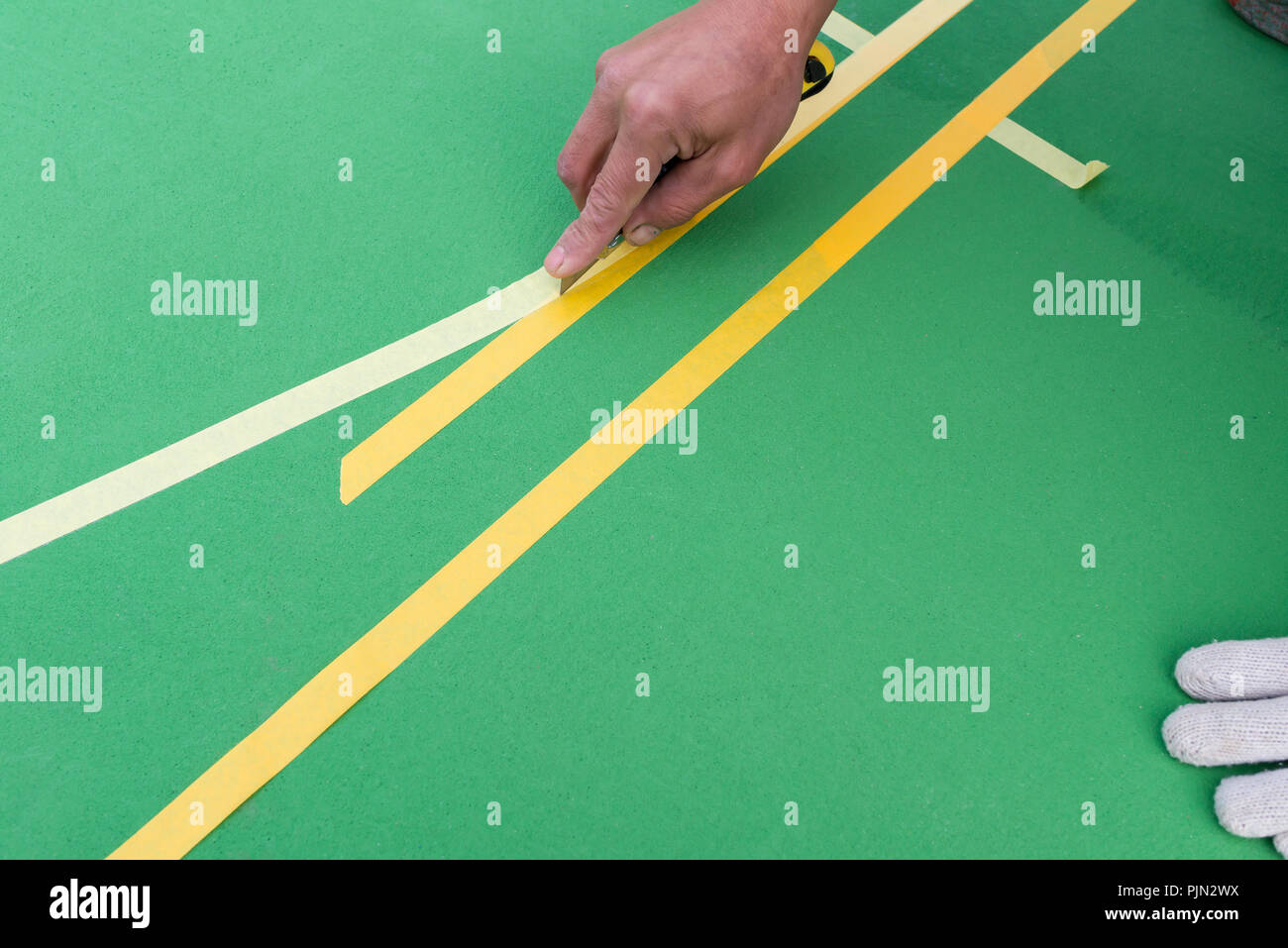 workers taping and marking the sideline on the floor for an outdoor ...
