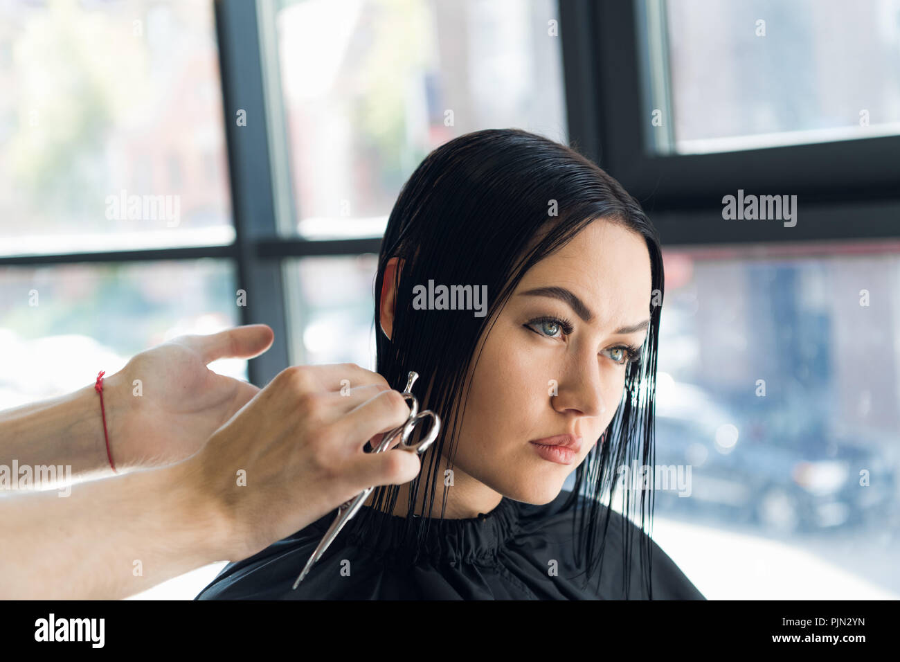 Hairdresser cutting hair of a beautiful serious brunette woman Stock ...