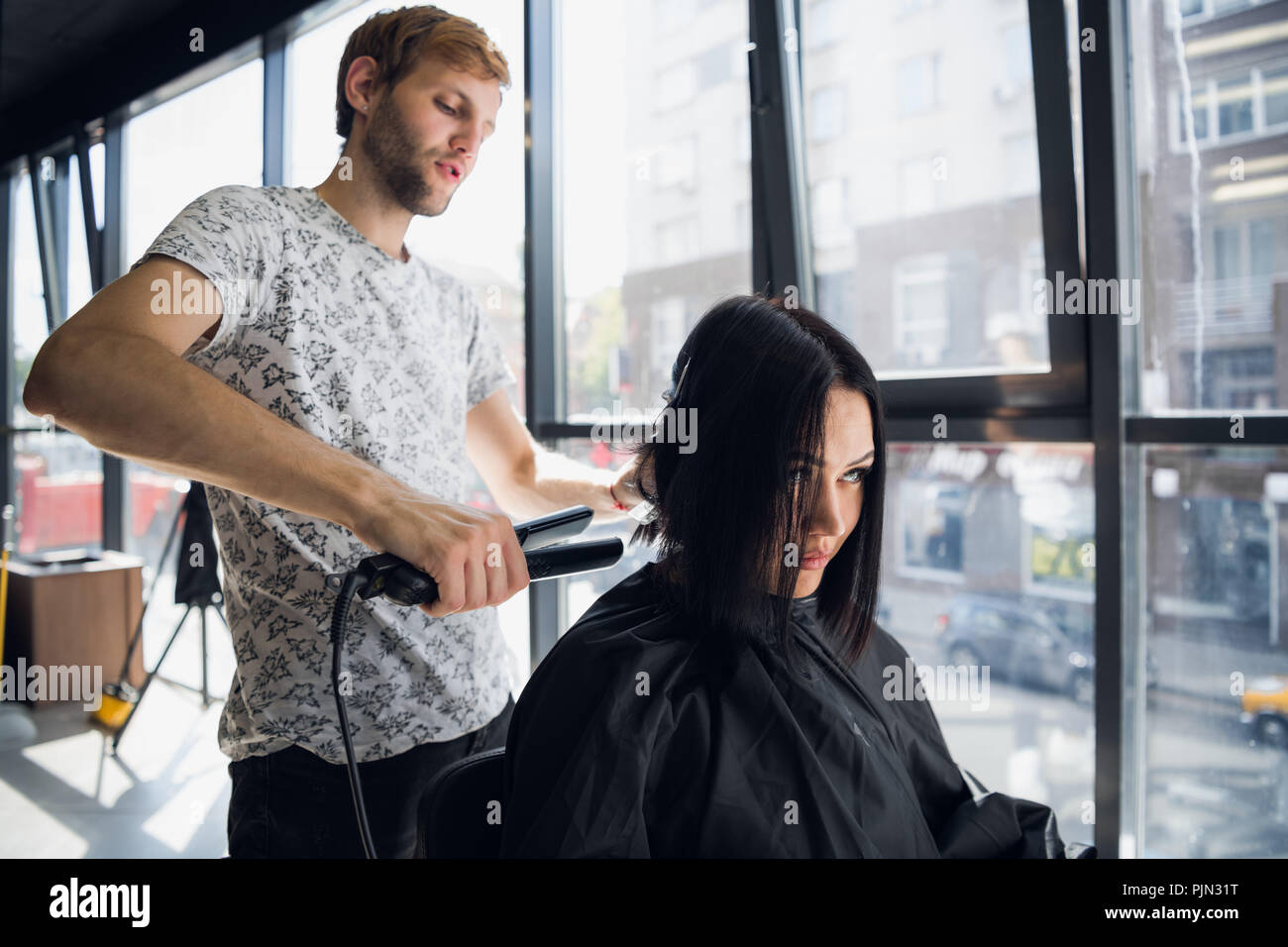 Beautiful woman happy while hairdresser is straightening her hair in ... Beautiful woman happy while hairdresser is straightening her hair in ...