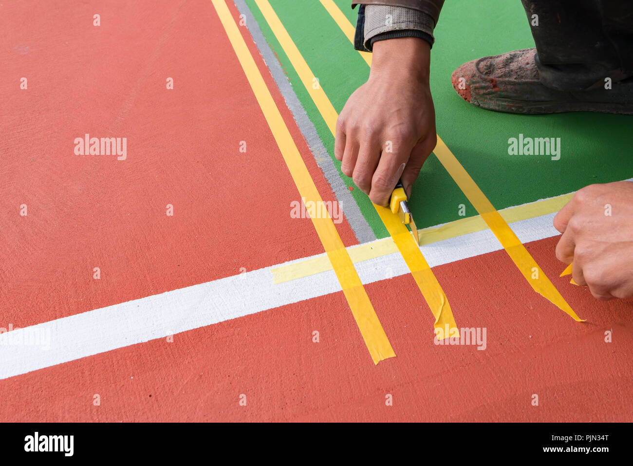 workers taping and marking the sideline on the floor for an outdoor ...