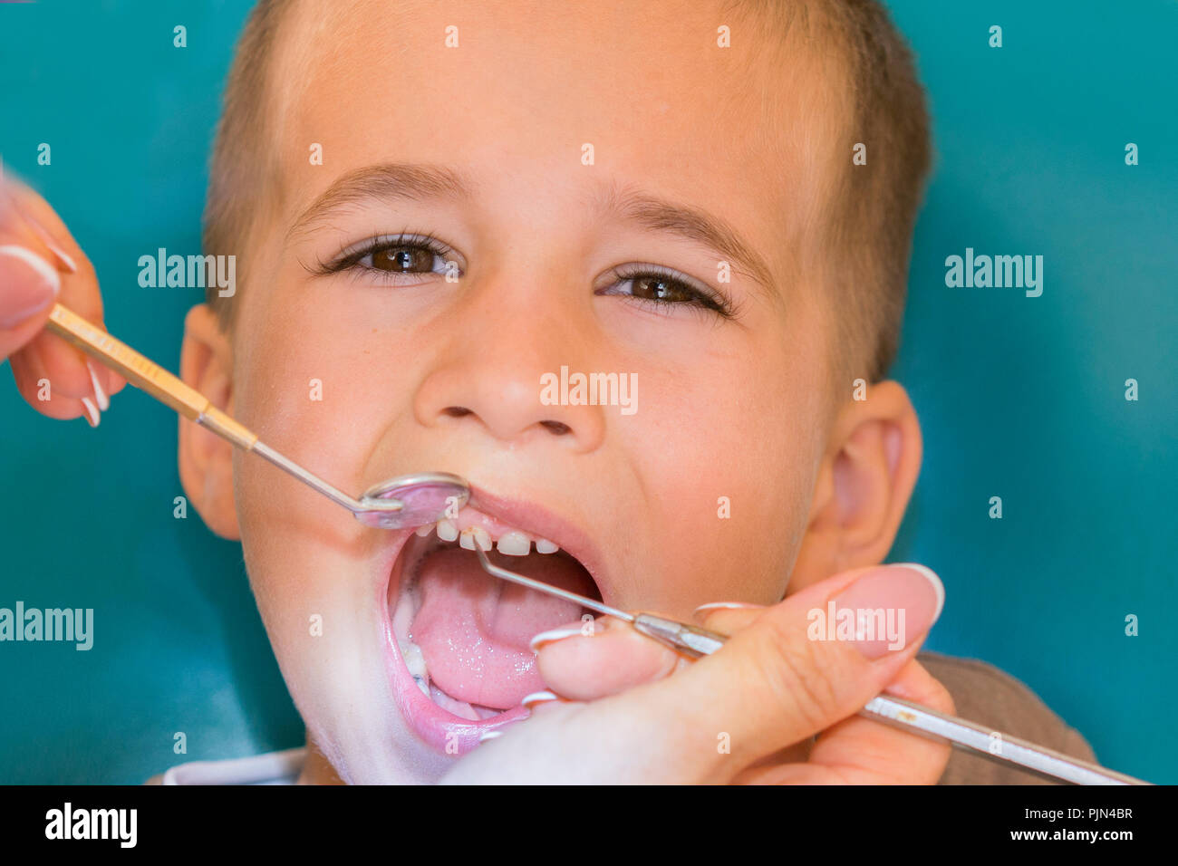 Dentist examining little boy's teeth in clinic. Close up of boy having ...